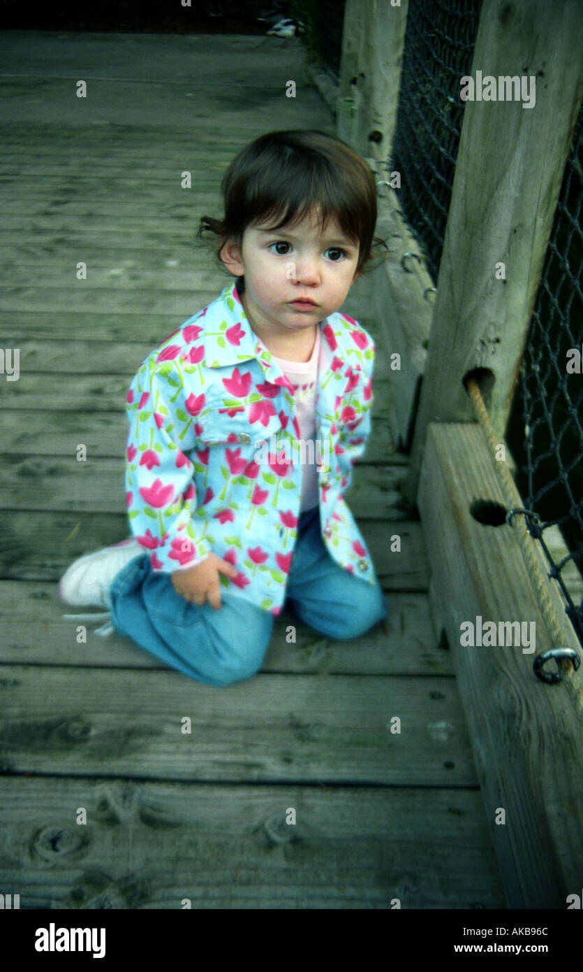 Child kneeling on bridge looking at you Stock Photo - Alamy