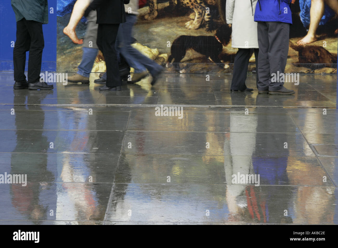 People reflected in rain soaked pavement Stock Photo - Alamy