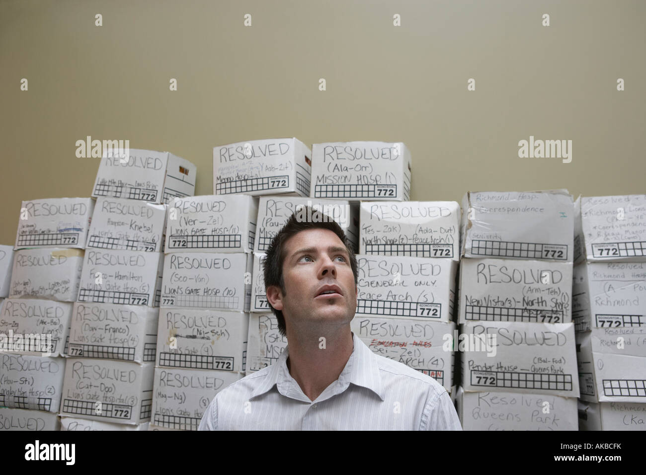 Business Man Standing In Front Of Stack Of Filing Boxes In Storage Room Low Angle View Stock