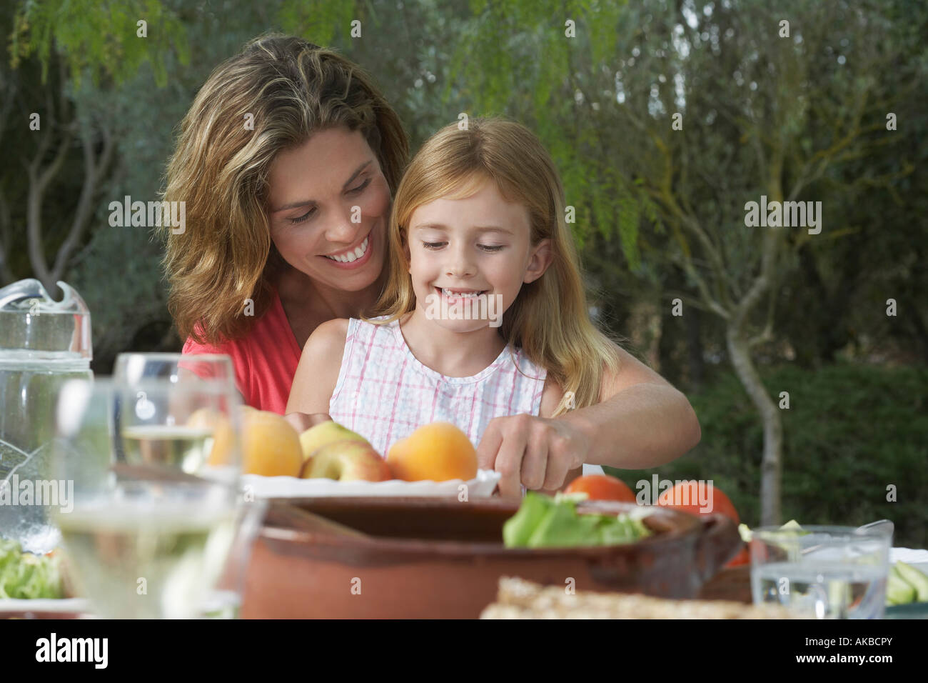 Mother and daughter (5-6) sitting at garden table, smiling Stock Photo ...