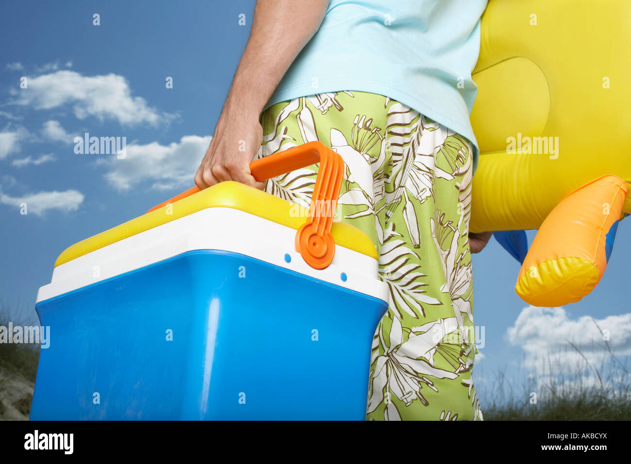 Man carrying inflatable toy and cool box, mid section, back view Stock ...