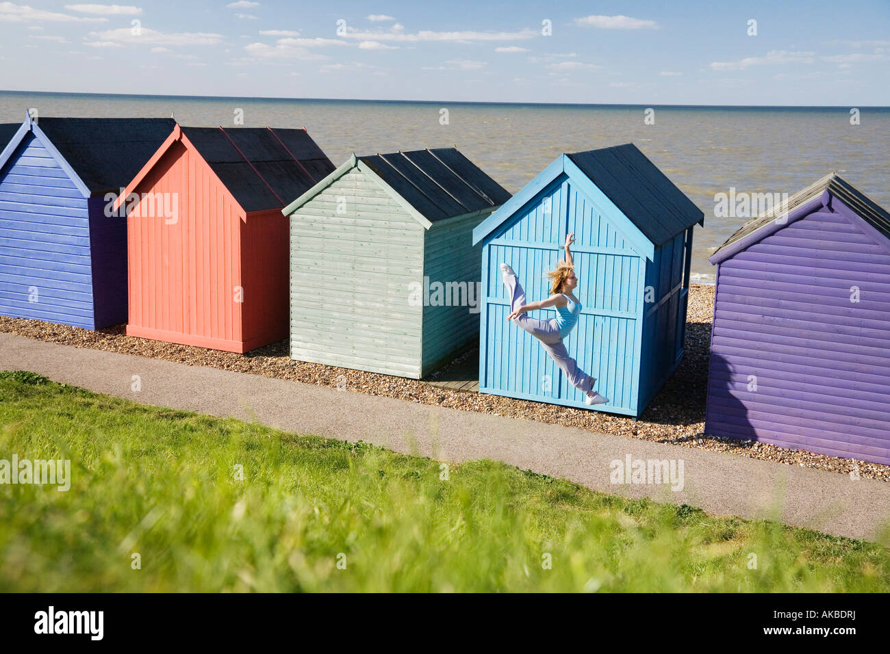 Woman jumping in front of beach hut Stock Photo - Alamy