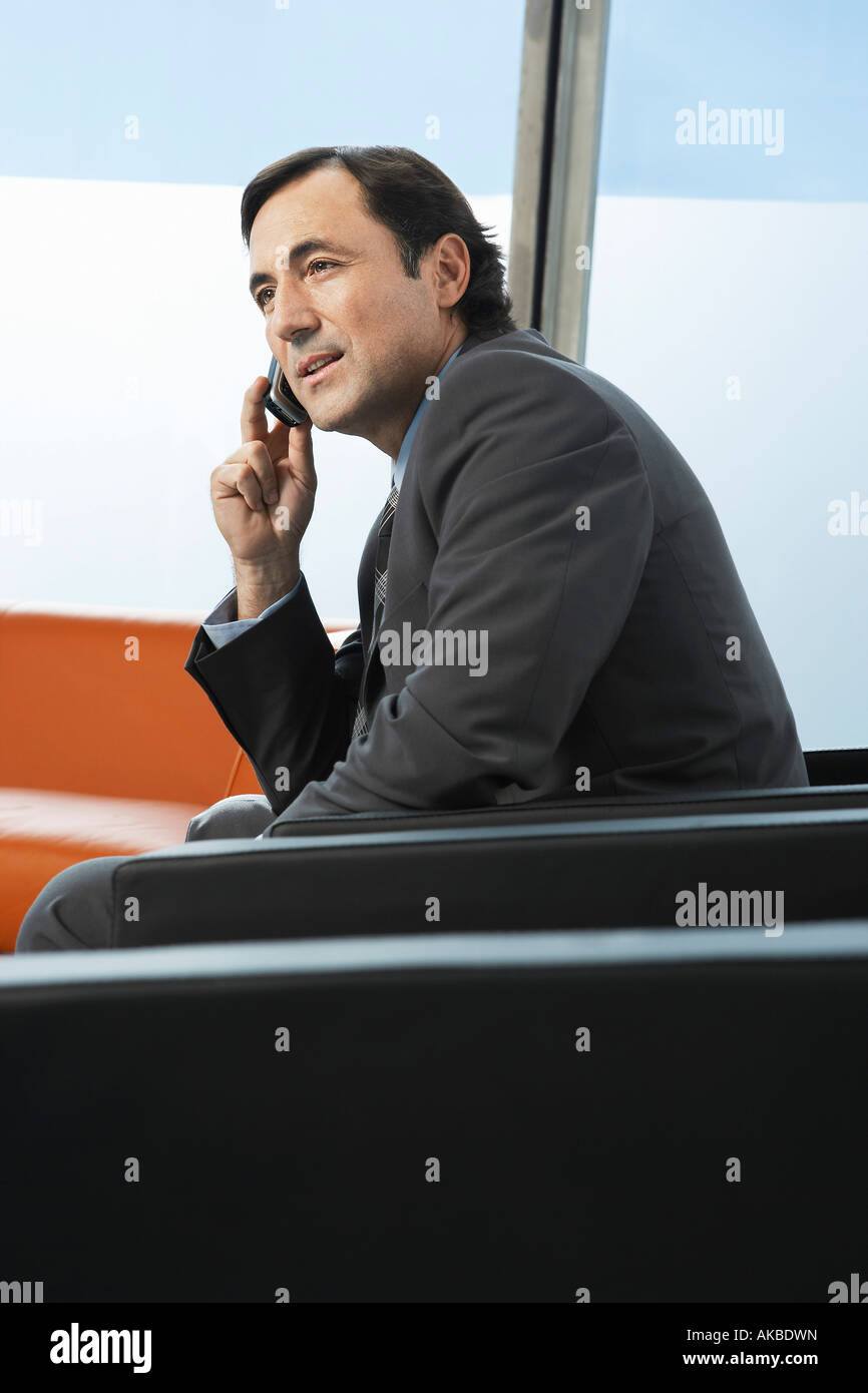 Business man using mobile phone, sitting in leather chair in office ...