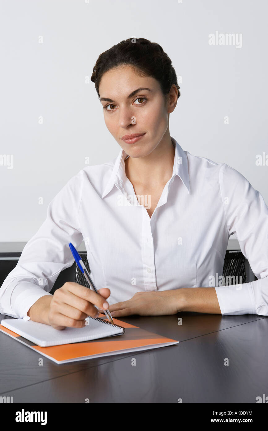 Business woman writing at desk in office, portrait Stock Photo - Alamy
