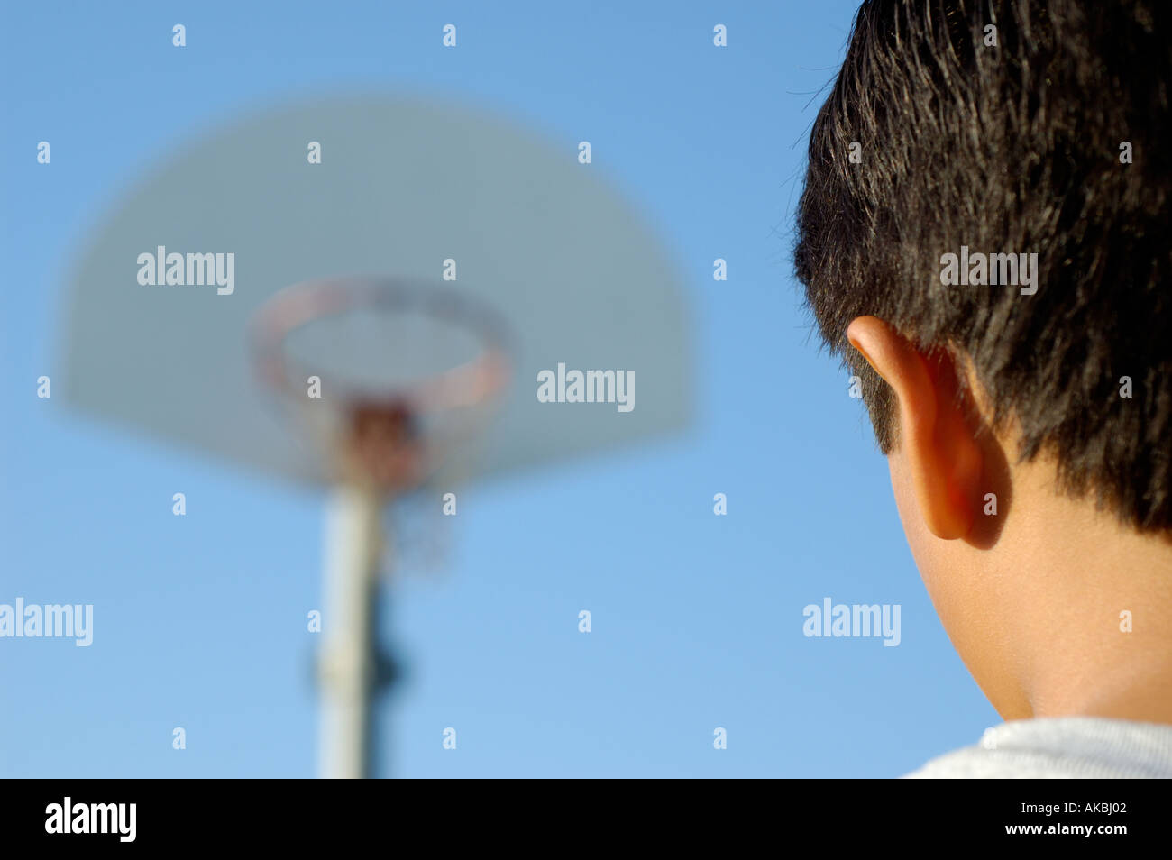 Young boy looking at basketball hoop Stock Photo - Alamy