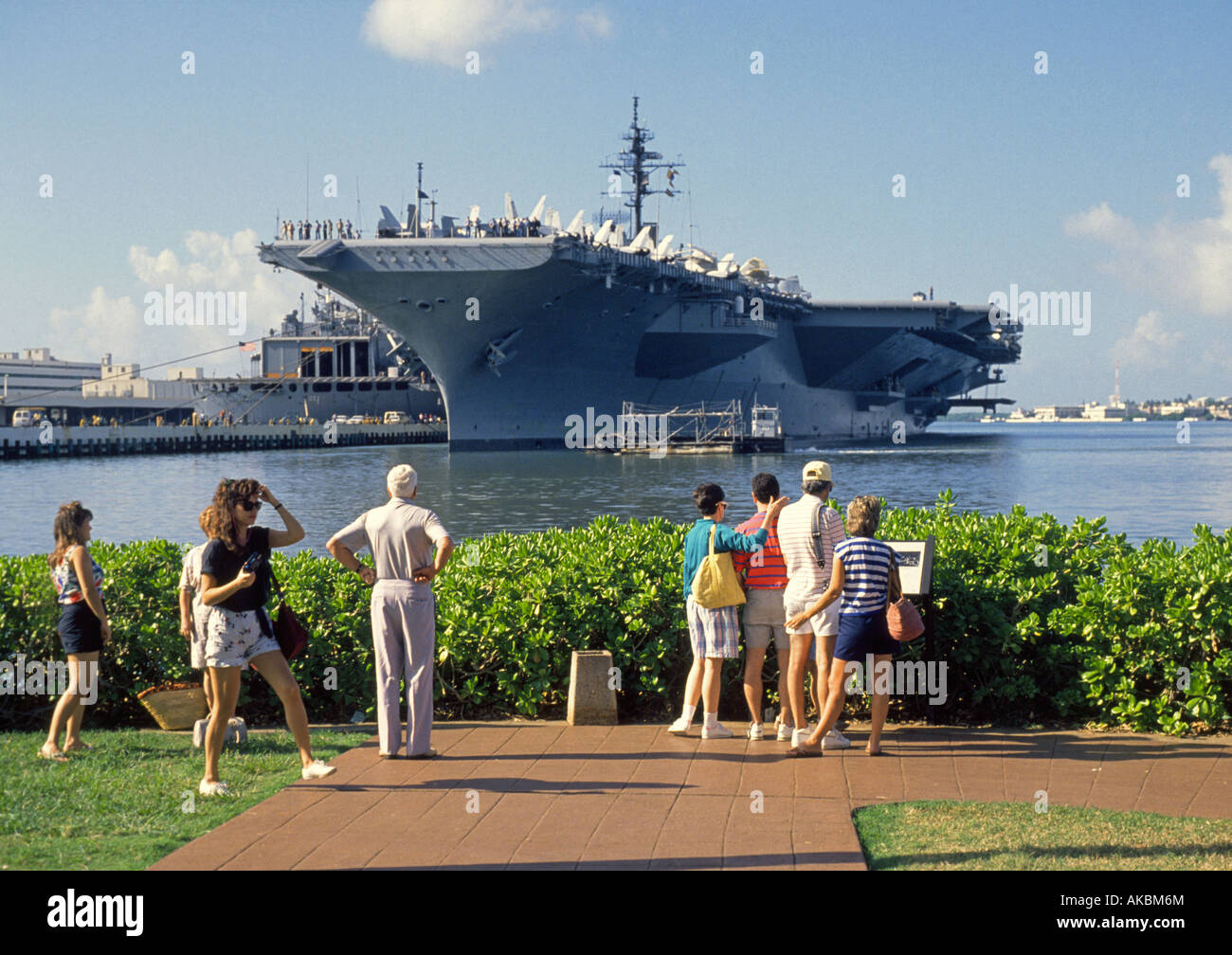 Visitors look at an American Aircraft Carrier moored at Pearl Harbor ...