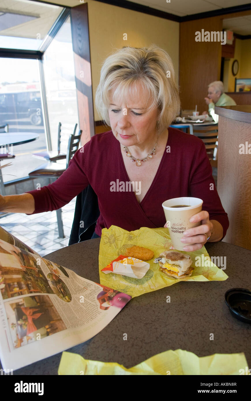 Adult female eating breakfast and reading at a fast food restaurant ...