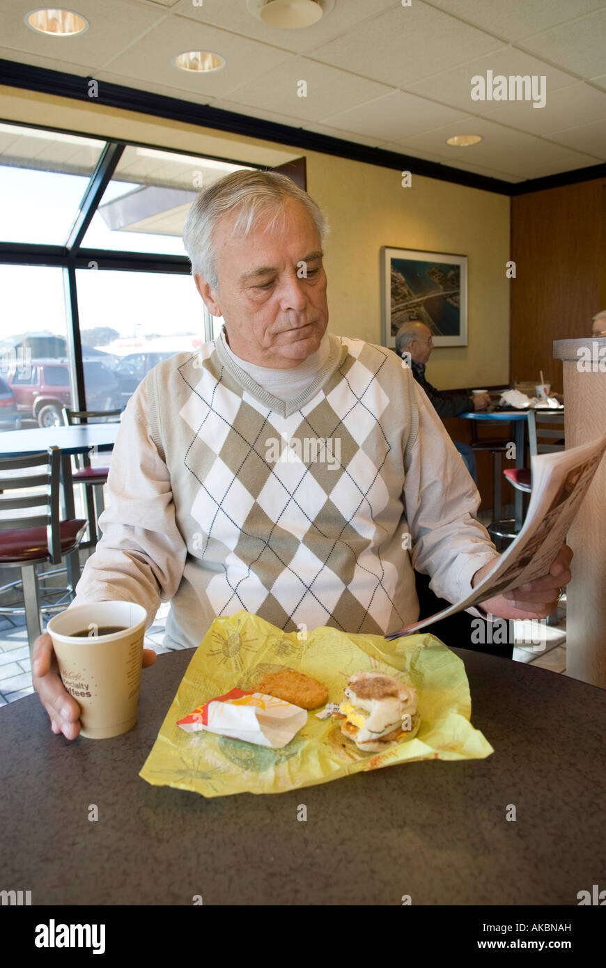 Adult male eating breakfast and reading at a fast food restaurant Stock ...