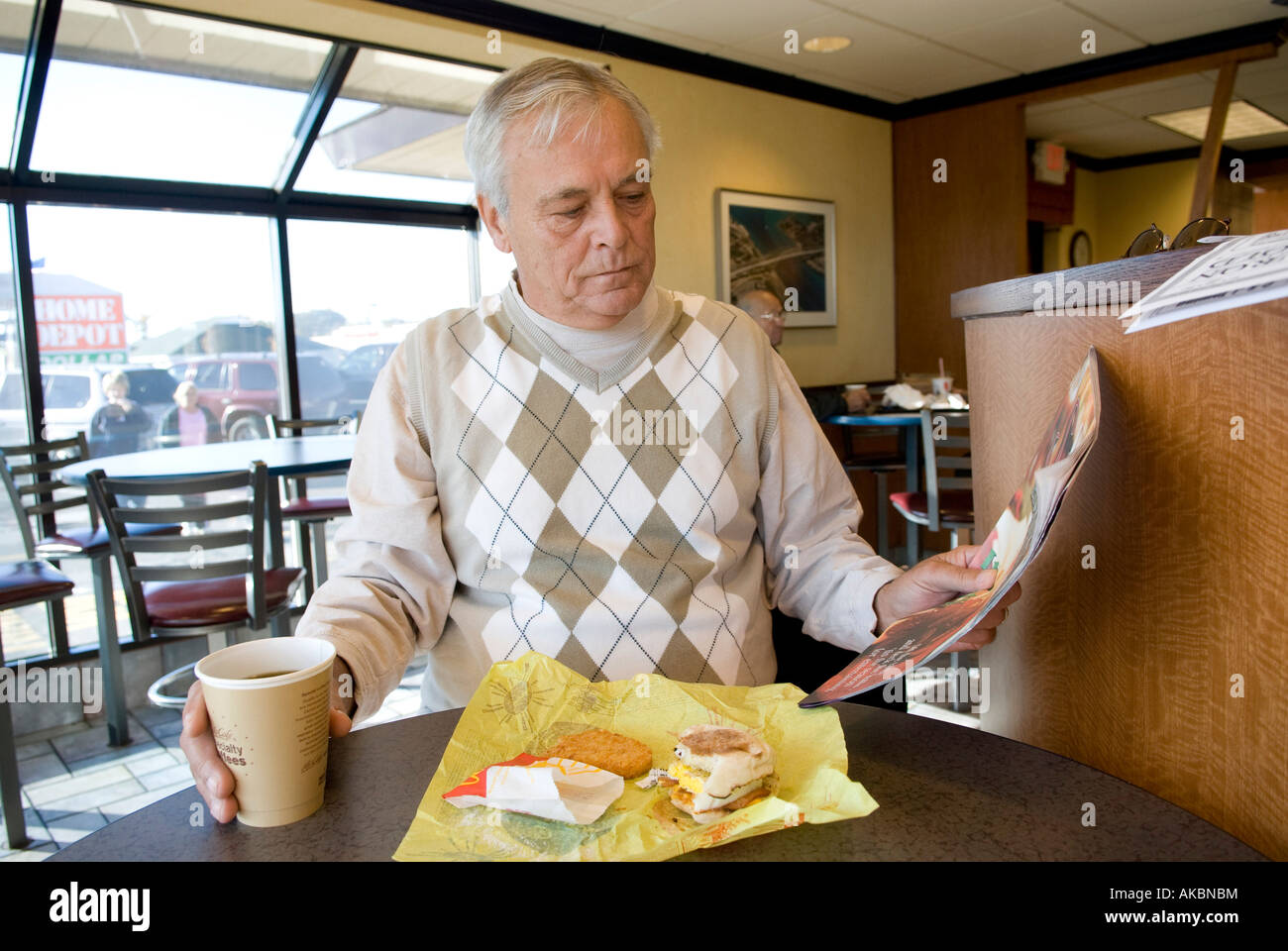 Adult male eating breakfast and reading at a fast food restaurant Stock ...