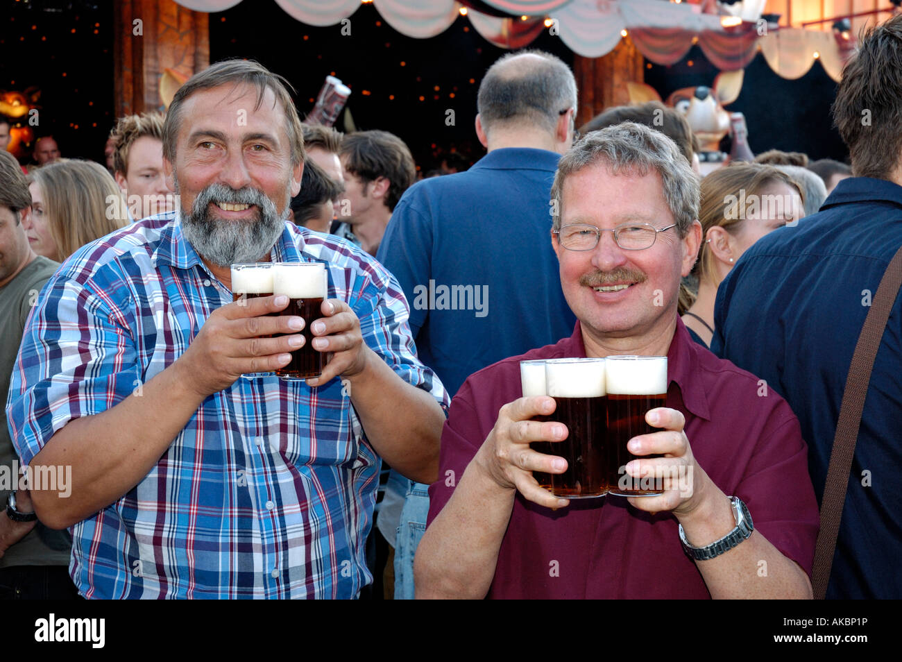 Two smiling middle-aged men 50's clasping full glasses of Alt beer ...