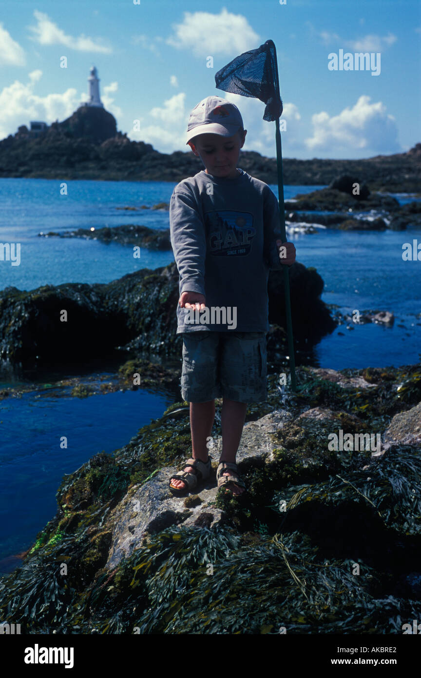 Child looking at rock pool in front of Corbiere Lighthouse Jersey ...