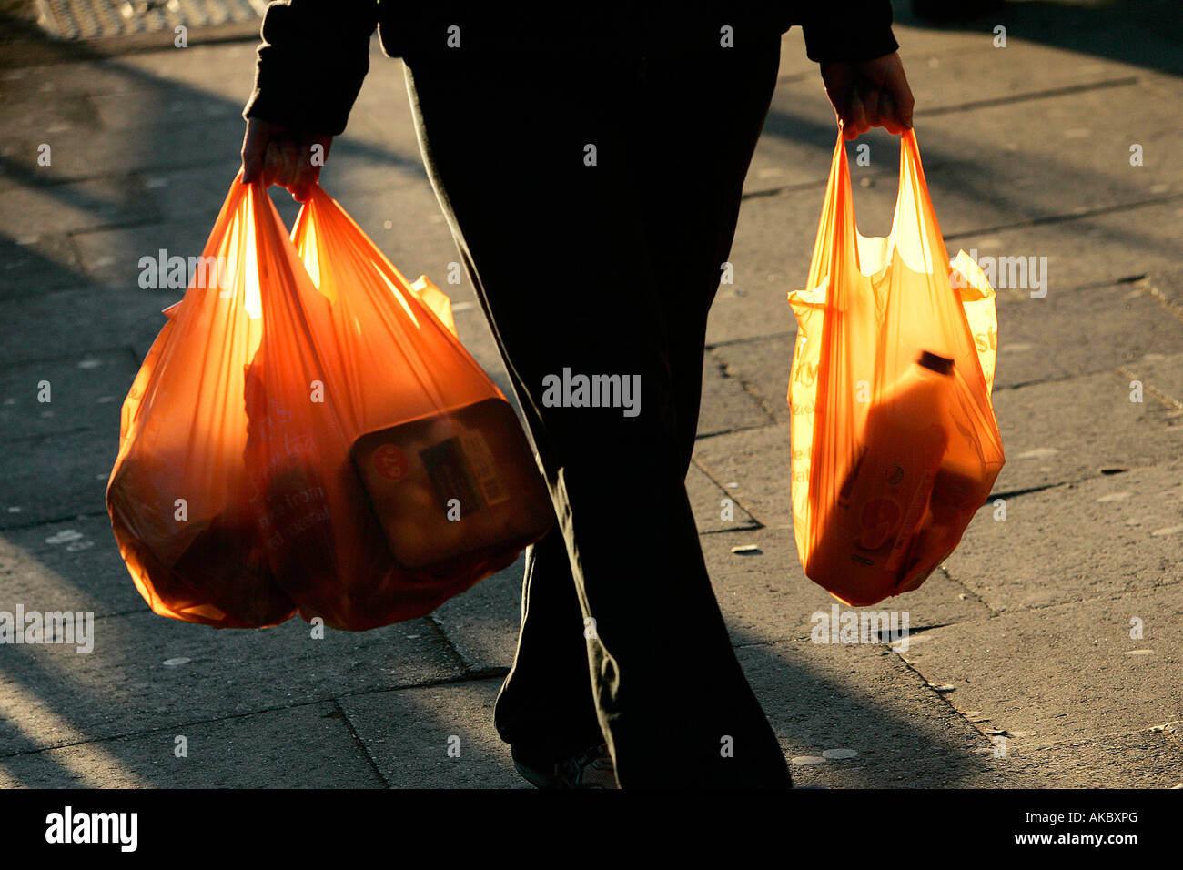Shoppers walk away from a supermarket holding plastic bags full of ...