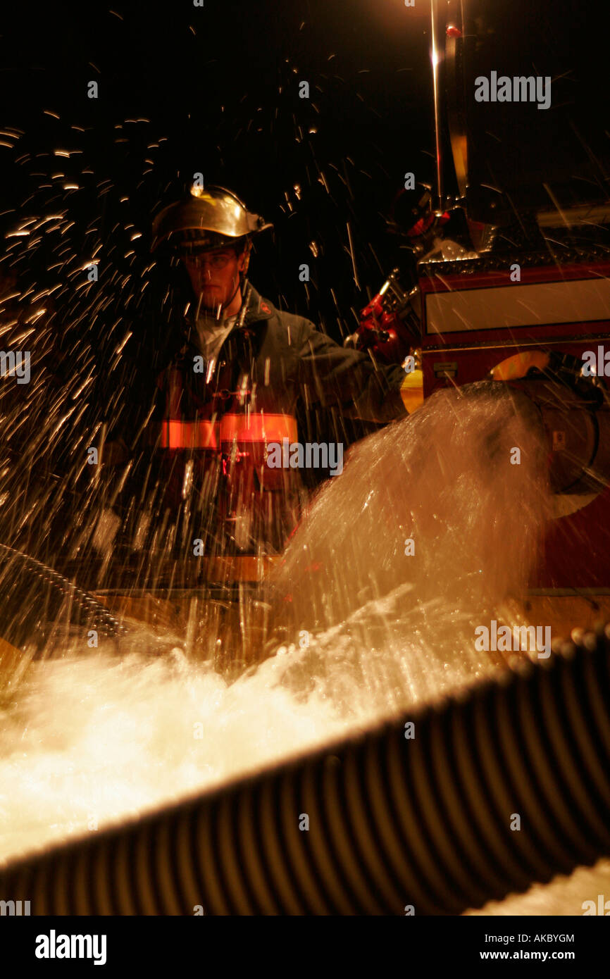 A firefighter at the controls of a water tanker valve releasing water ...