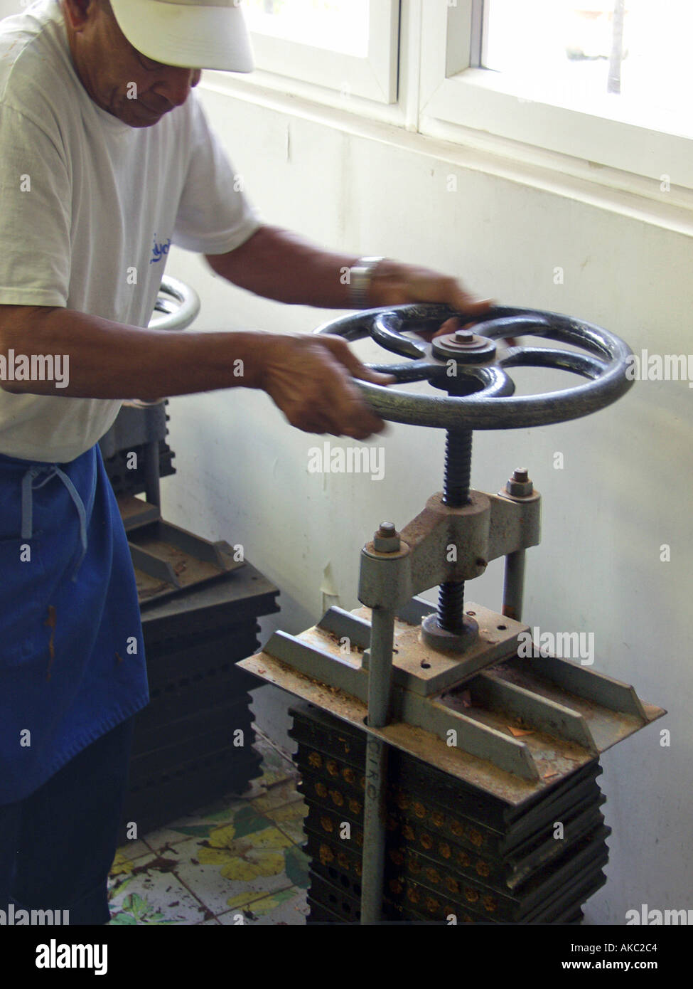 A Cuban cigar maker turns the handle of a press to compact newly rolled ...