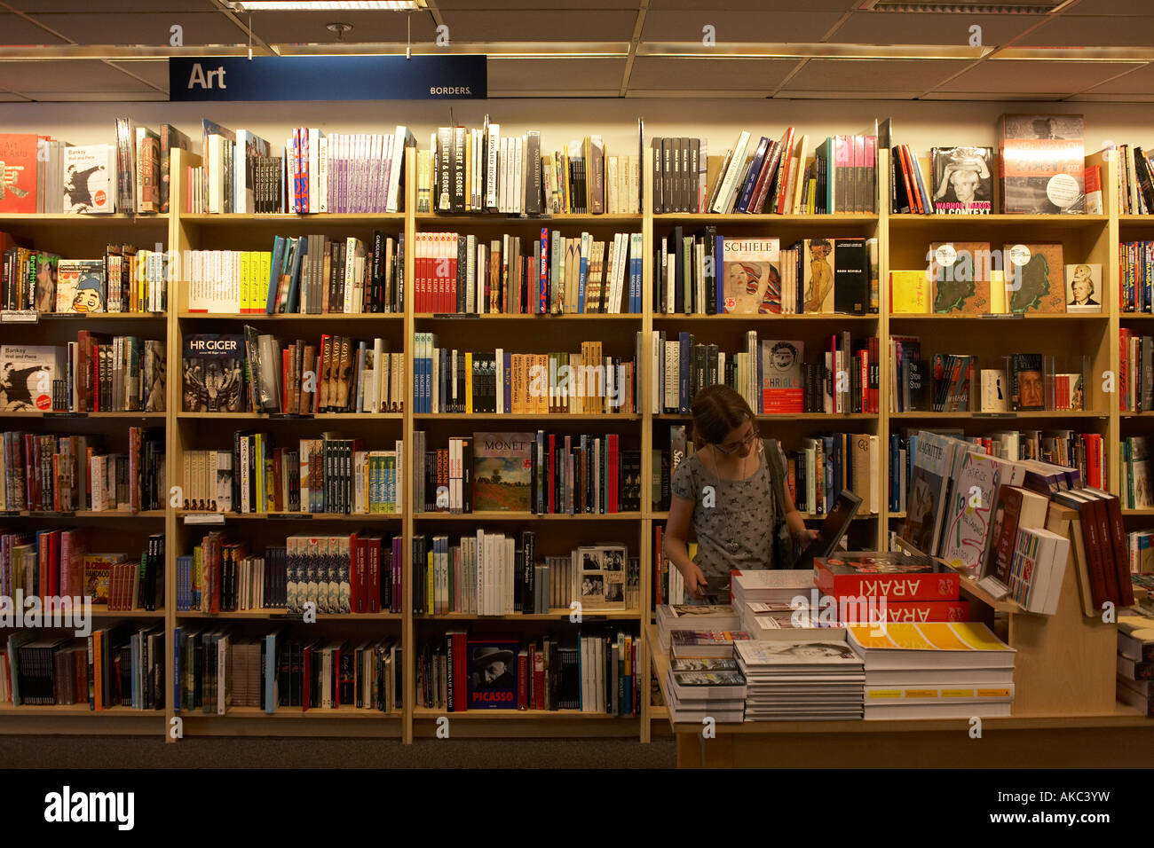 Surrounded by books a young 12 year old girl intently browses Art books ...
