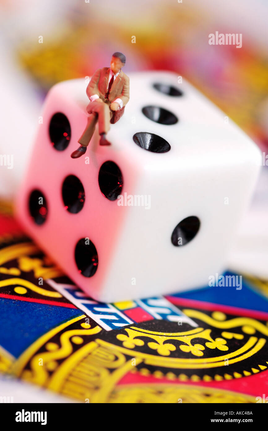Tiny male figure in business suit sitting on dice and playing cards ...