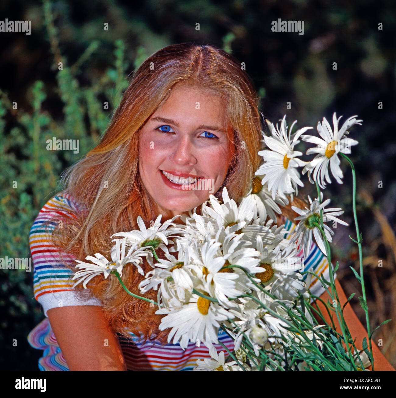 Young attractive glonde girl holding an armfull of Shasta Daisy blooms ...