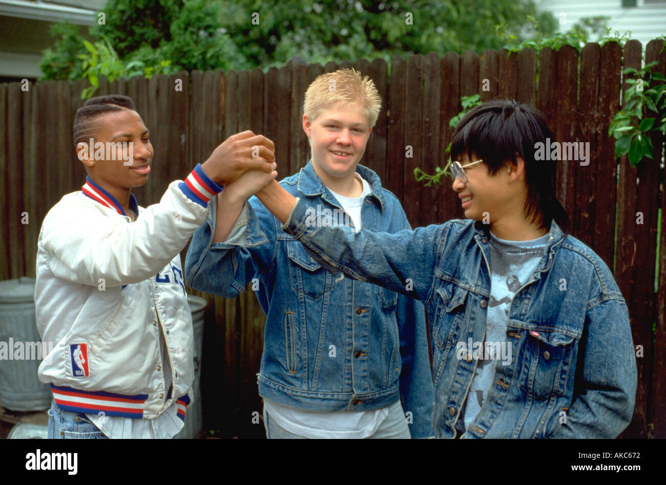 Multicultural teens age 15 doing high five in alley. St Paul Minnesota ...