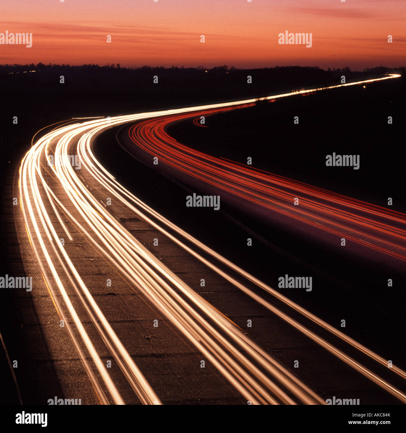 Sunset beyond vehicle light trails three lane dual carriageway highway ...