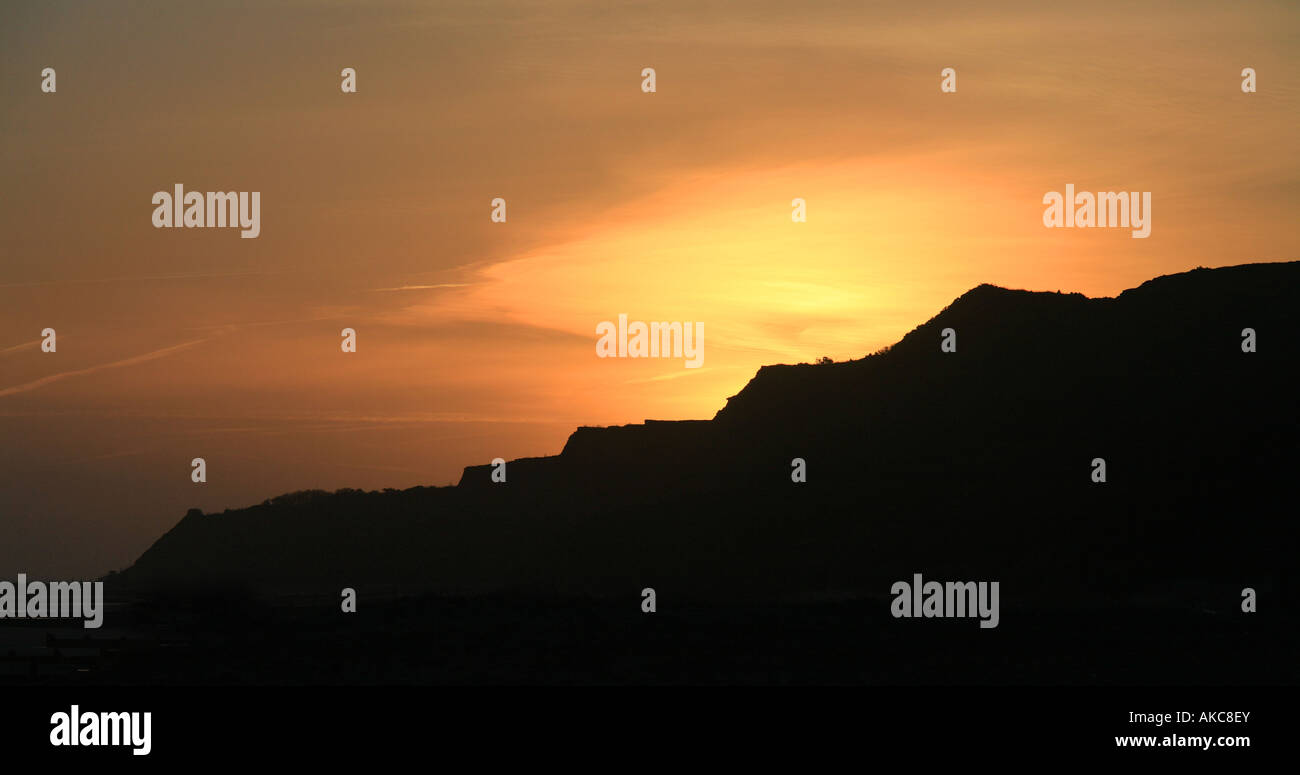 Brilliant golden glow as sun rises behind cliffs at Cromer, Norfolk, UK ...