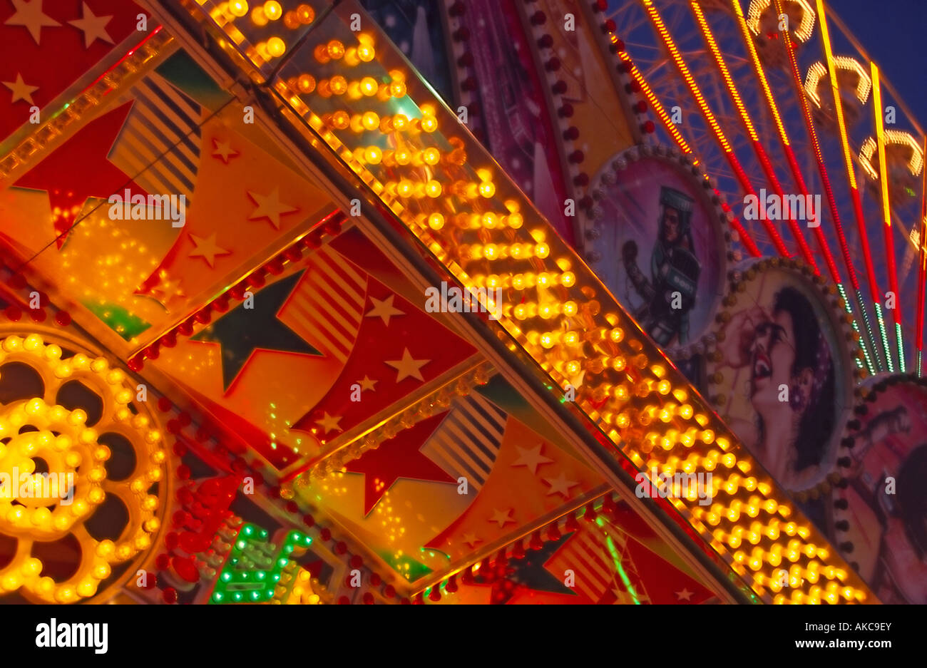 fair with lightened racing amusement rides in different colours in the ...