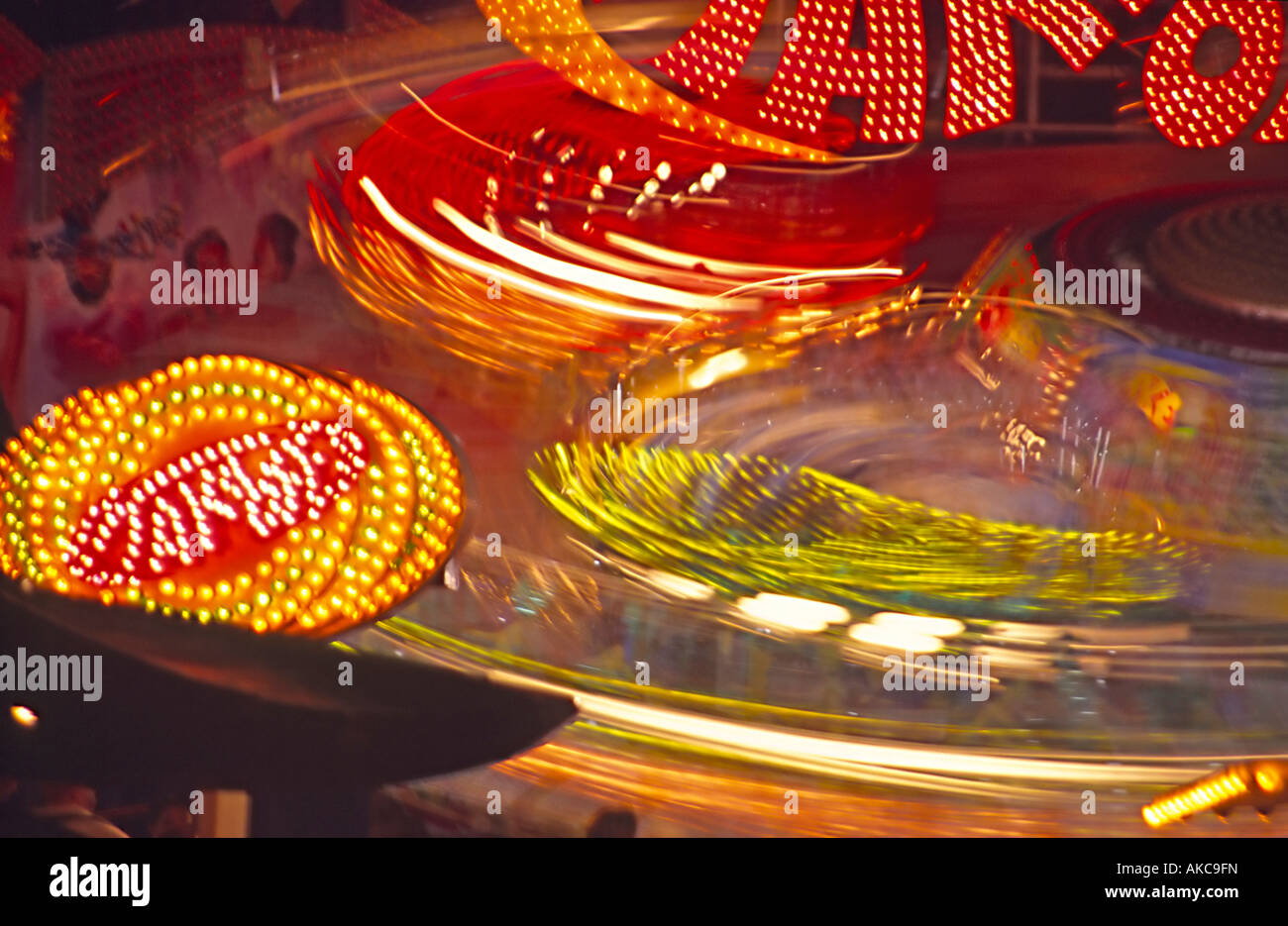fair with lightened racing amusement rides in different colours in the ...