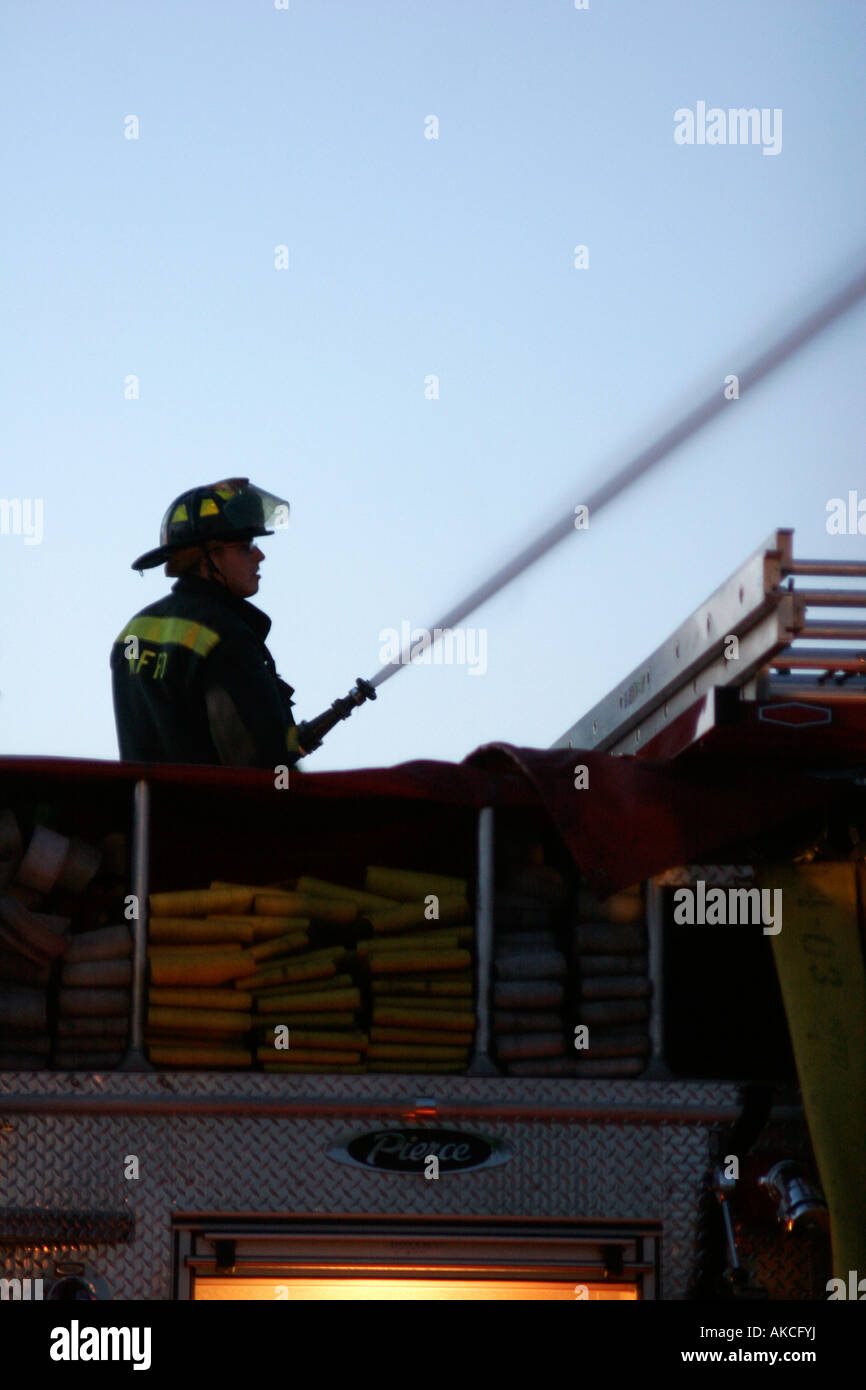 A firefighters at the controls of the hose pumping from the fire truck ...