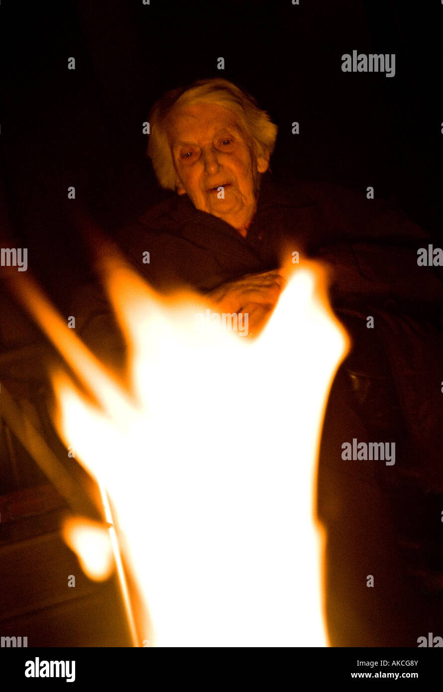 Elderly lady by fire at night Stock Photo - Alamy