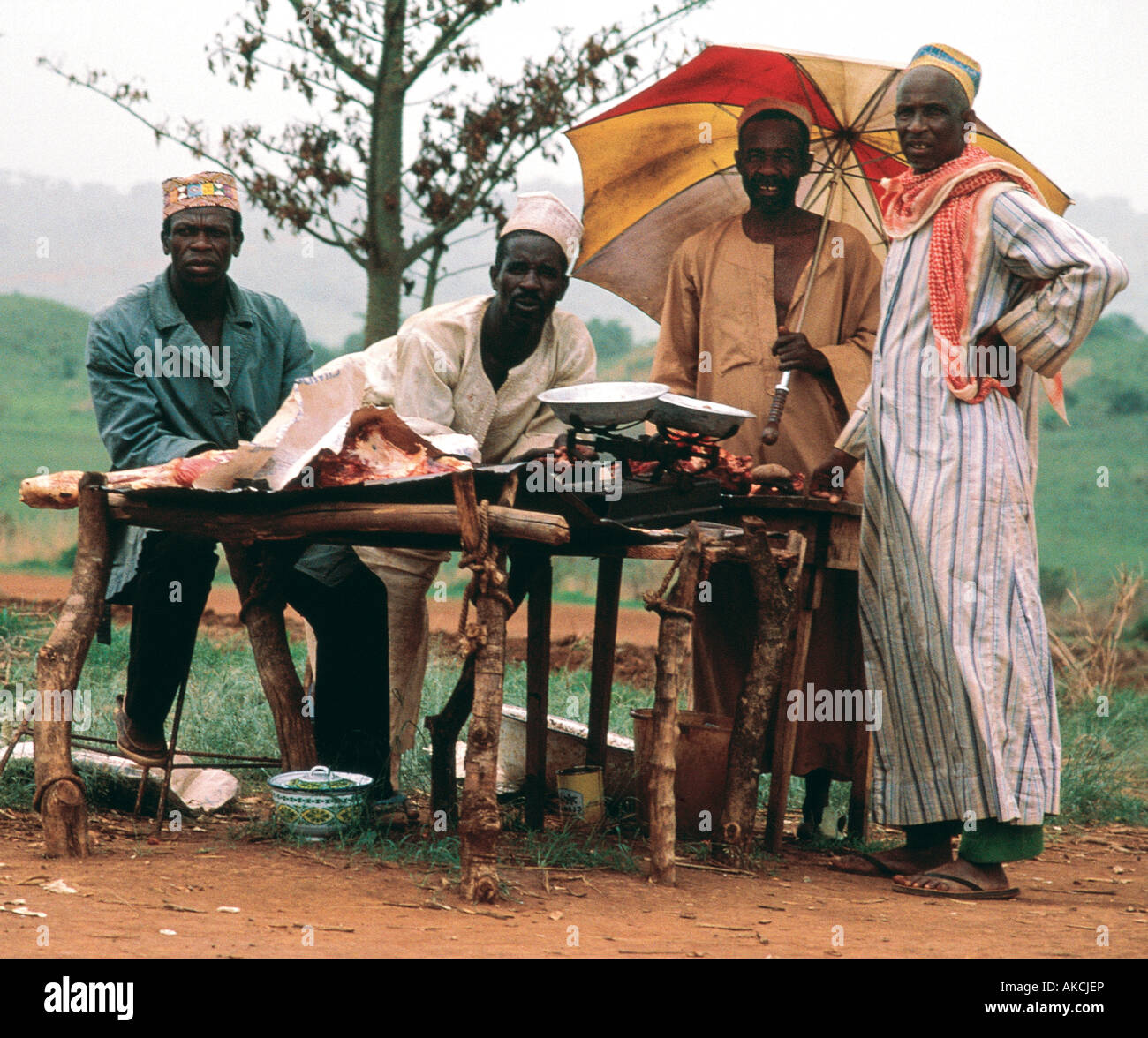 Four African men selling meat at a road side stall in the north of the ...