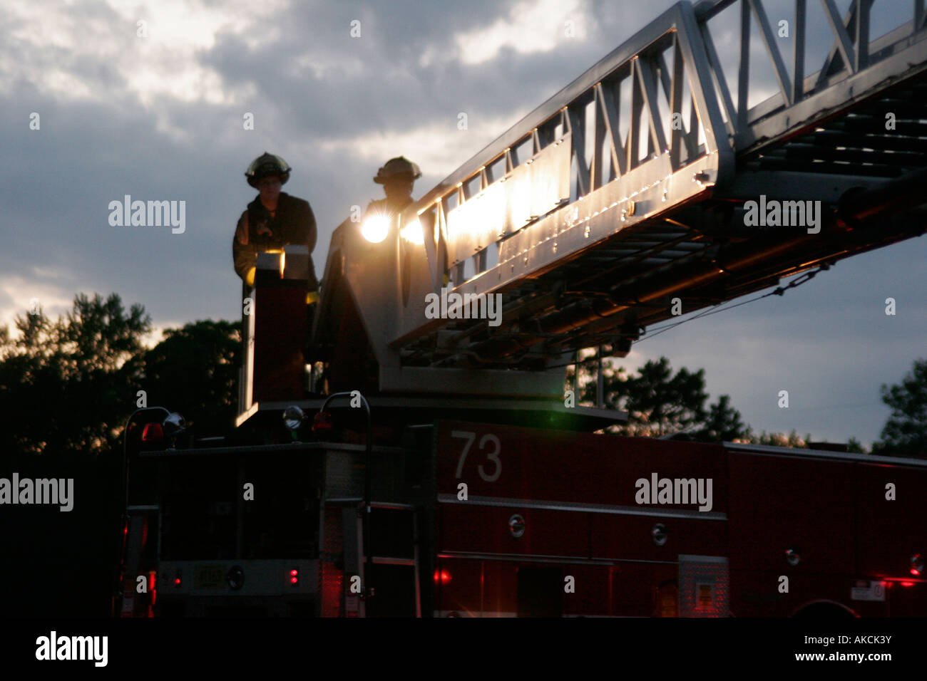 Two fire fighters at the controls of a ladder truck Stock Photo - Alamy