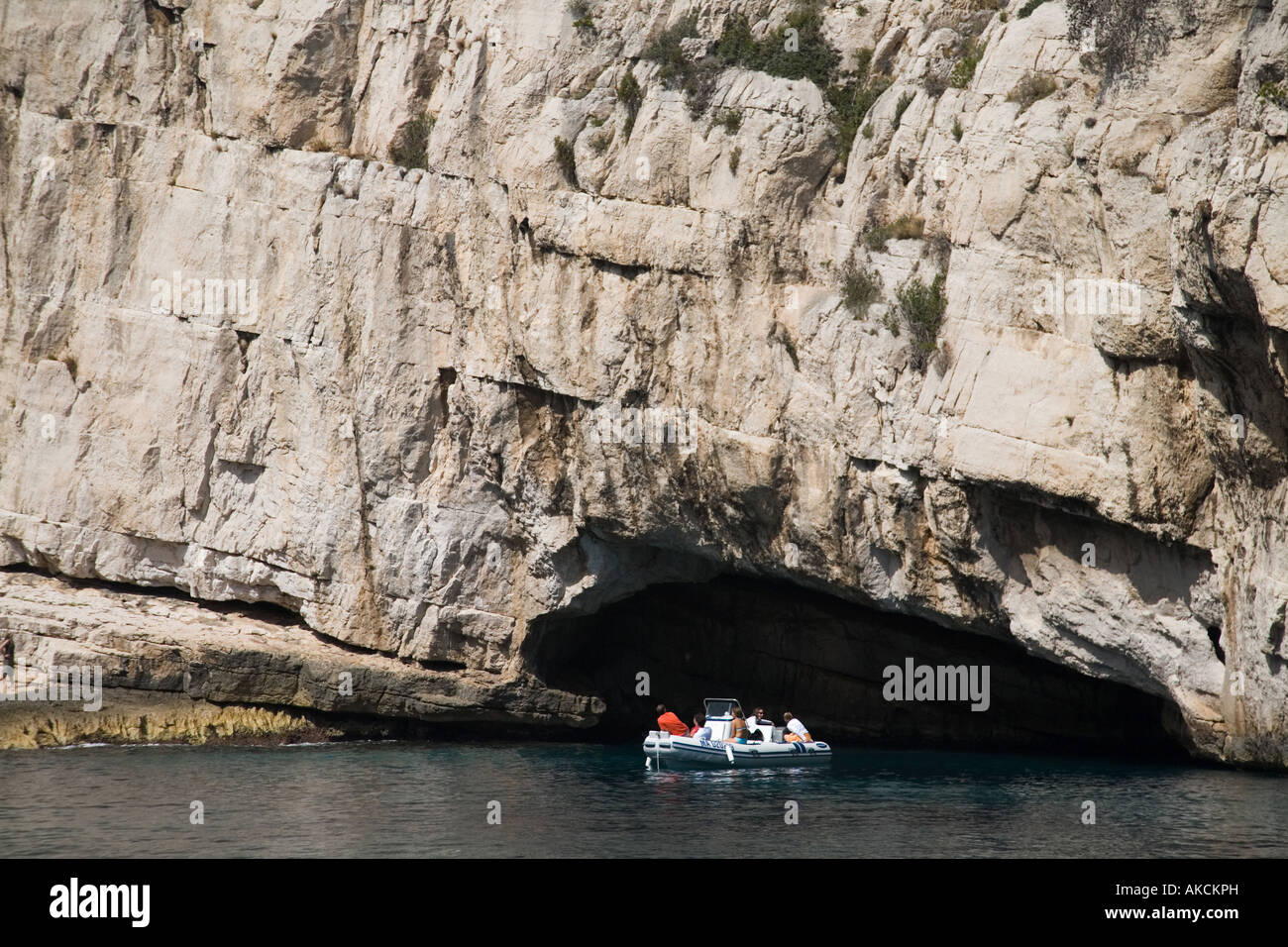 Small outboard boat in a cave under large cliffs Stock Photo - Alamy