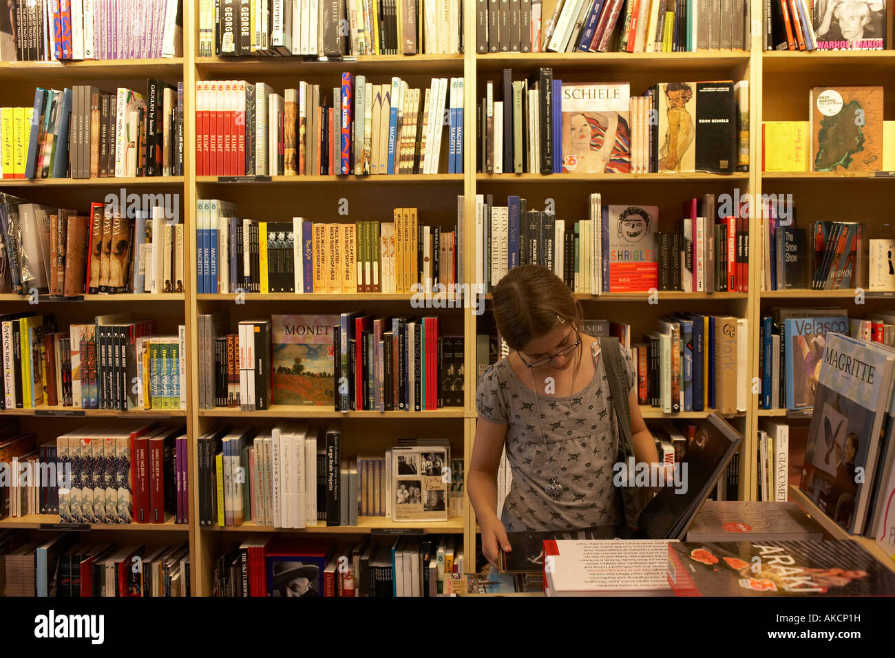 Surrounded by books a young 12 year-old girl intently browses Art books ...