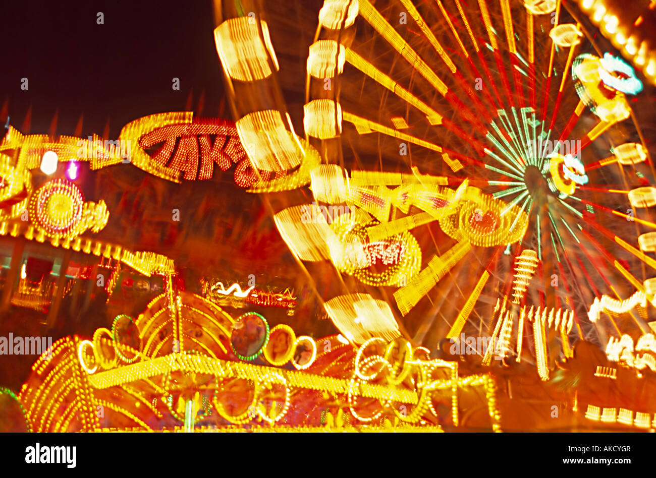 fair with lightened racing amusement rides in different colours in the ...