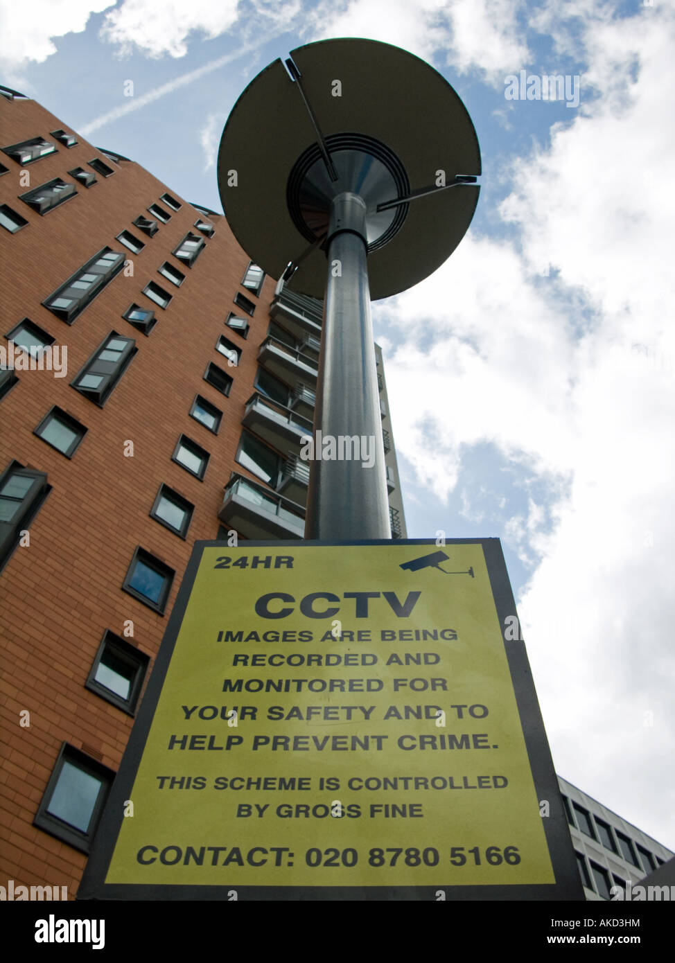 CCTV warning sign on a lampost beside a high-rise block of luxury flats ...