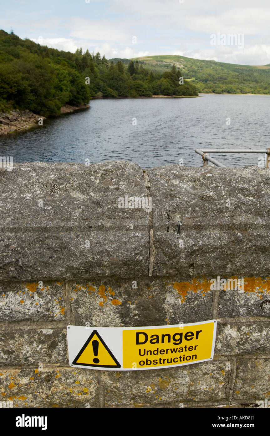 Yellow danger sign on Burrator reservoir dam wall situated on the edge ...