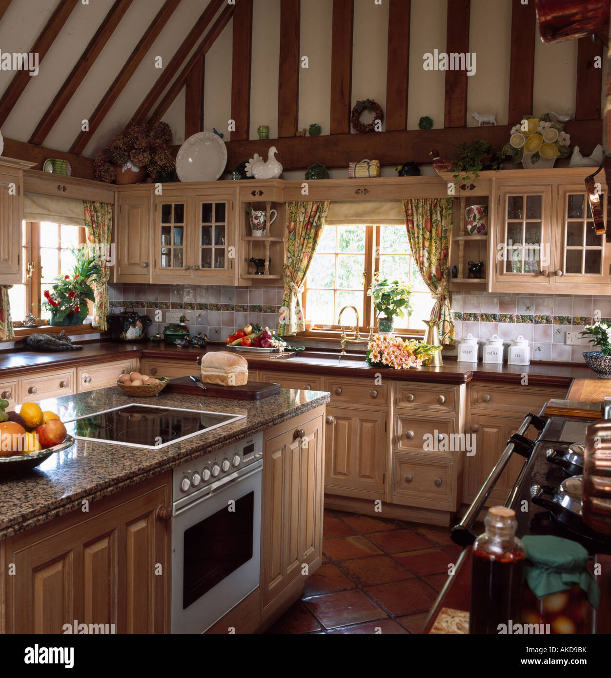 Oven and hob in island unit in barn conversion kitchen with beamed apex ...