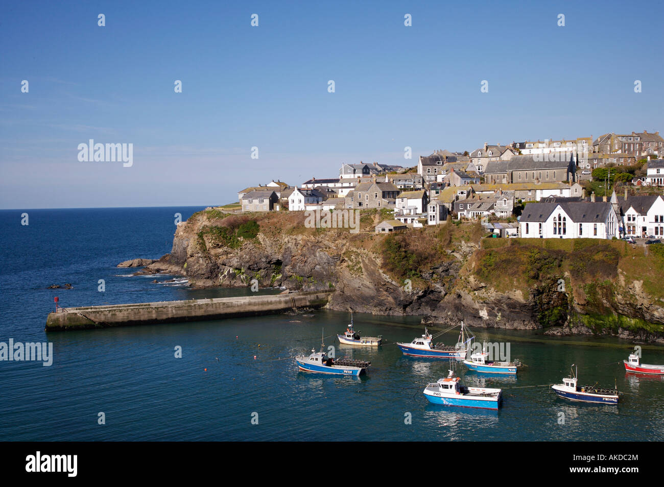 Small boats in the harbour below cottages on the cliffs at Port Isaac ...