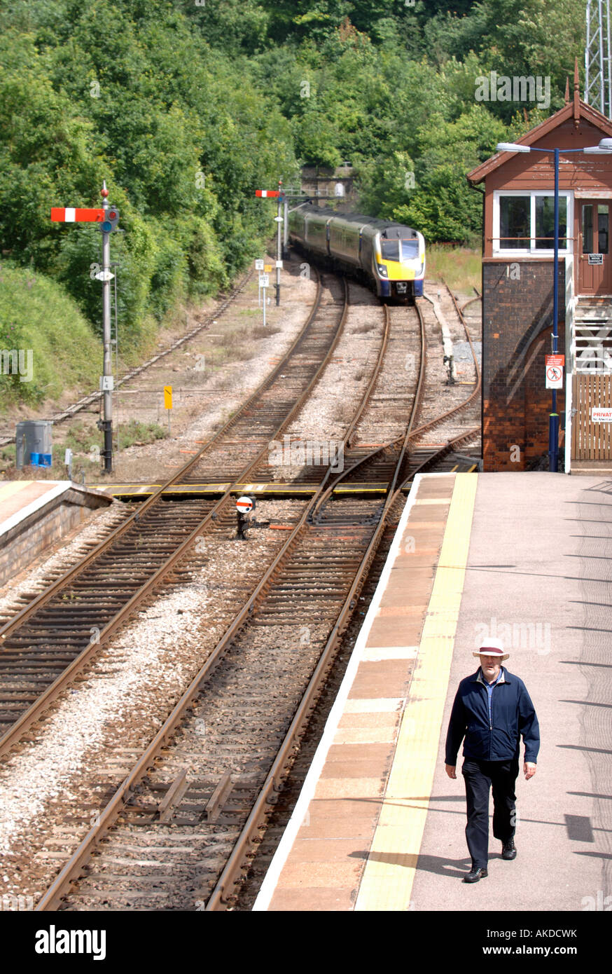 A MAN WALKS ALONG THE PLATFORM OF LEDBURY RAILWAY STATION AS A TRAIN ...