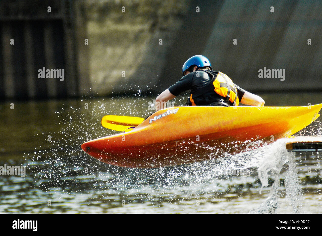 Kayaker in his orange playboat sliding off a ramp into the river Foss ...