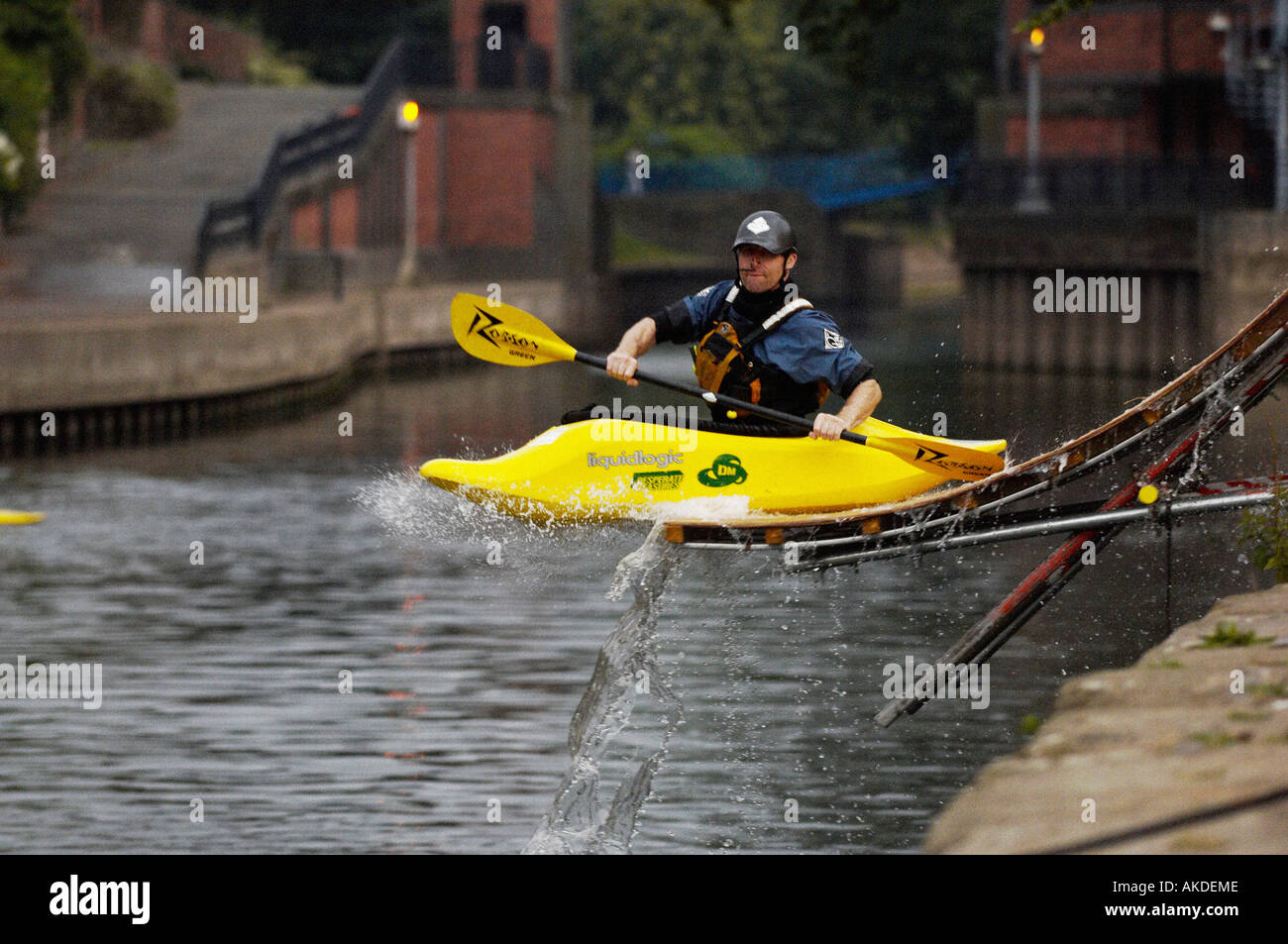 Kayaker in his yellow playboat sliding off a ramp into the river Foss ...