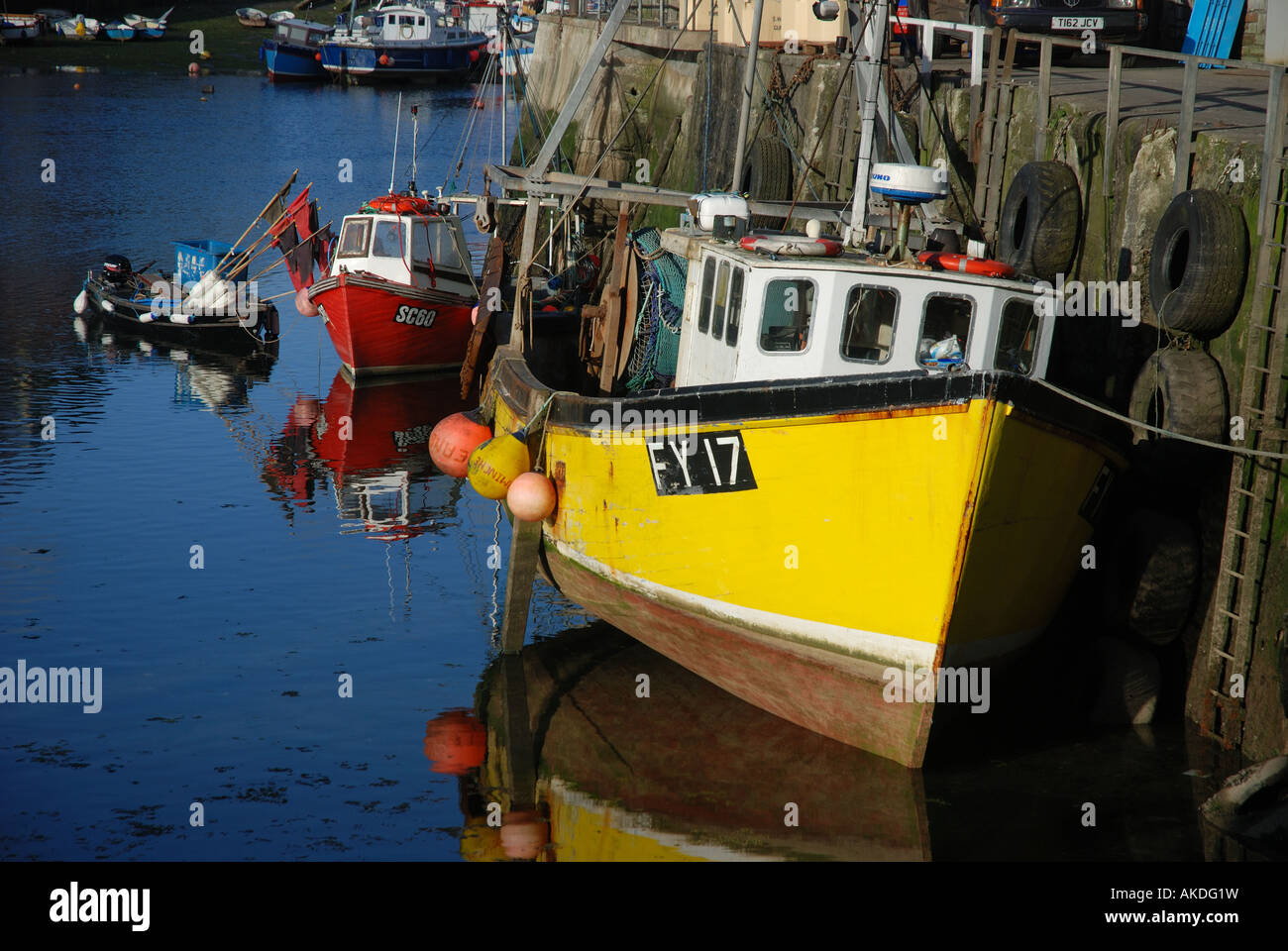 Yellow Fishing boat moored in Cornish fishing harbour on a warm summer ...