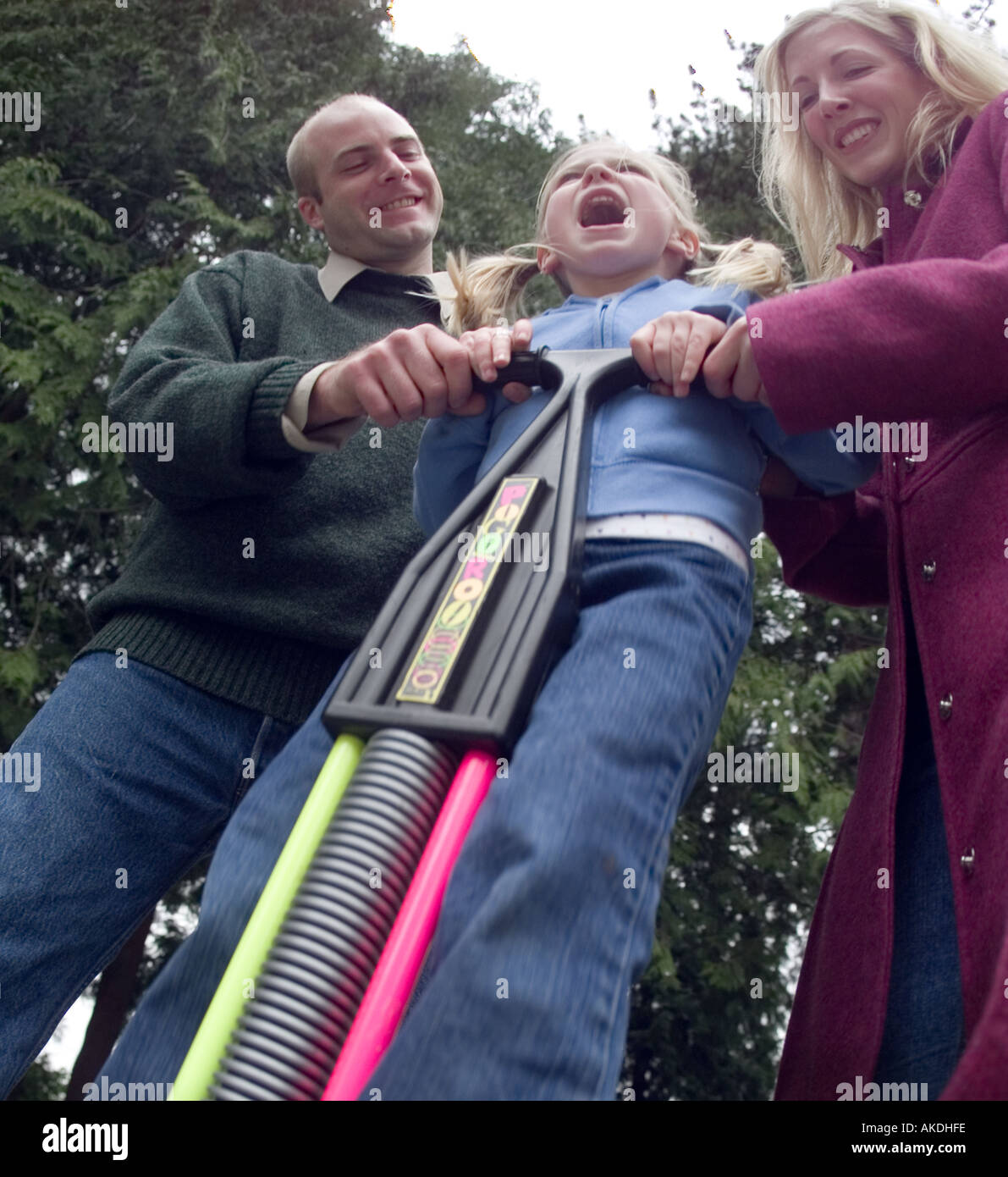 Caucasian parents helping daughter learn pogo stick Stock Photo - Alamy