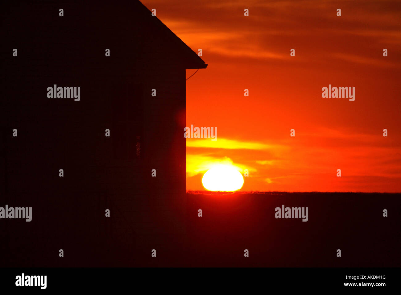 Sun setting behind old building Stock Photo - Alamy