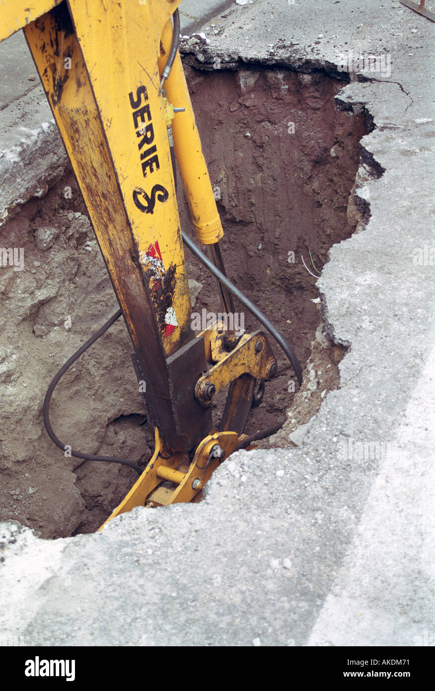 mechanical digger digging hole in road Stock Photo - Alamy