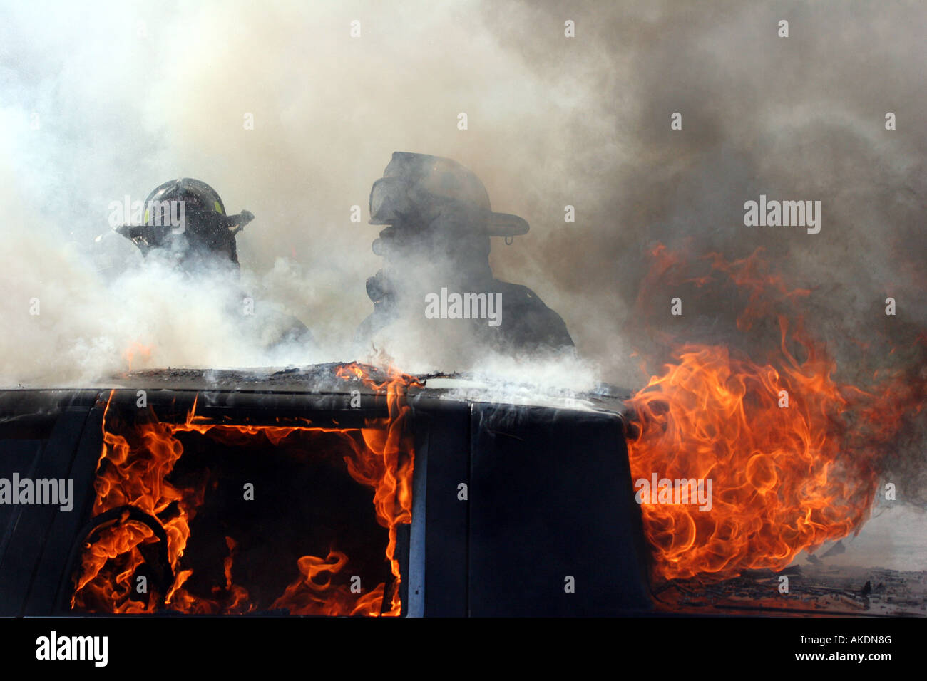 Two firefighters in smoke and steam trying to extinguish an auto fire ...