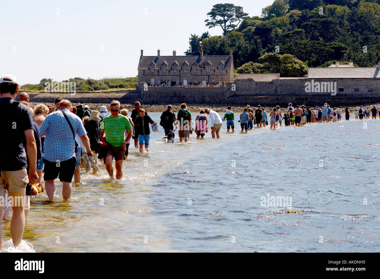 Visitors wade across a causeway, submerged in seawater to and from the ...