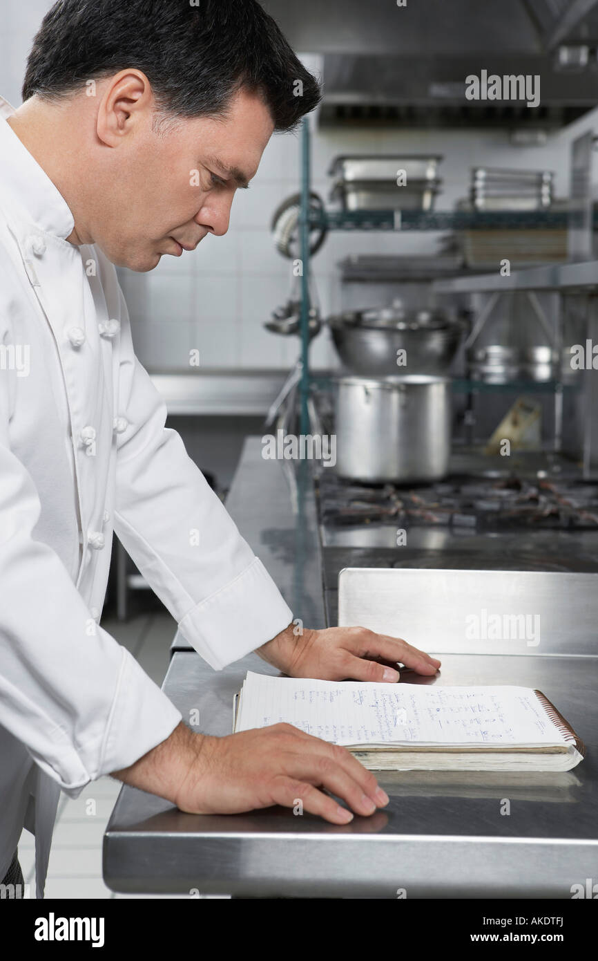 Male chef reading recipe book in kitchen Stock Photo - Alamy
