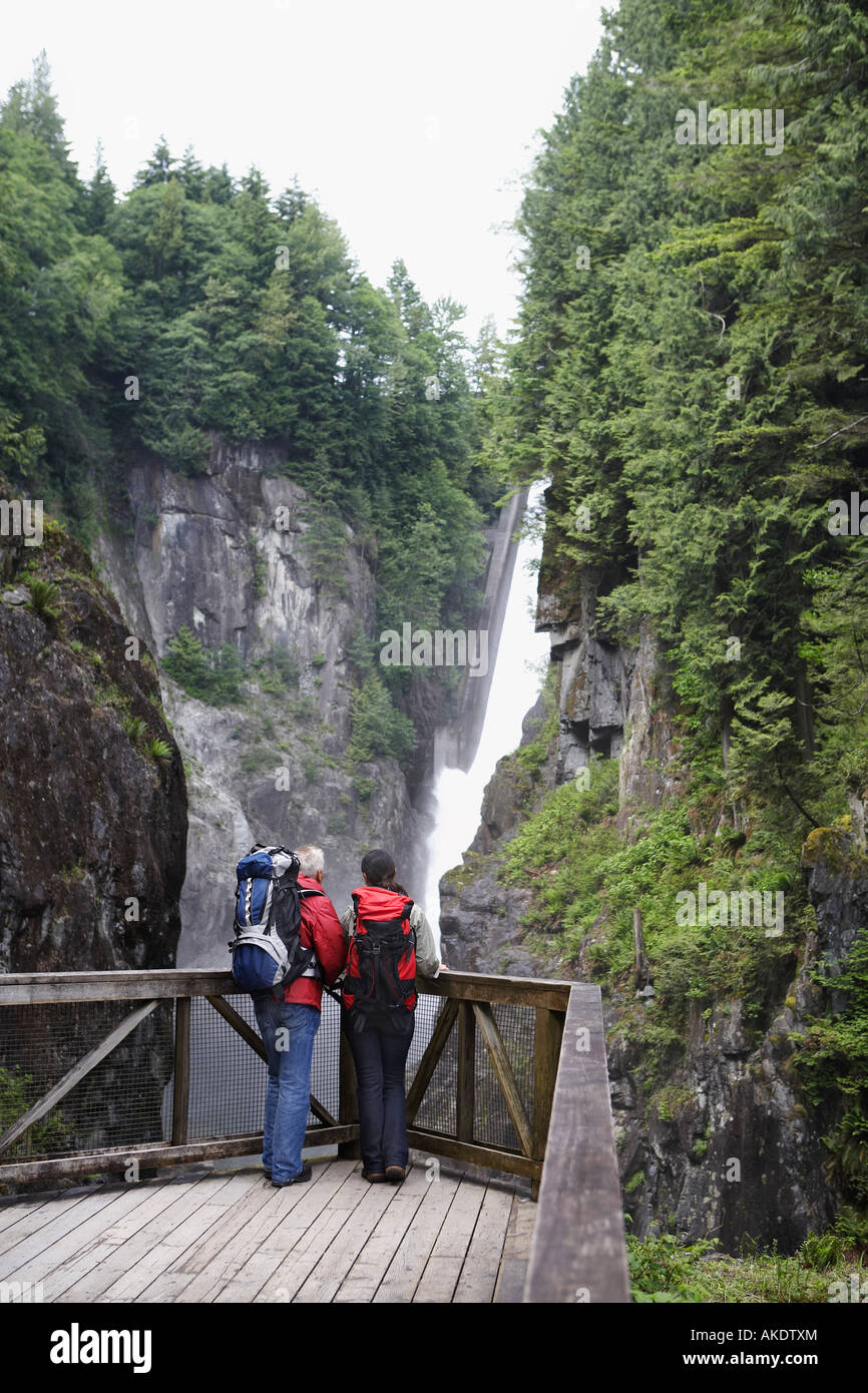 Man and woman watching waterfall, back view Stock Photo - Alamy