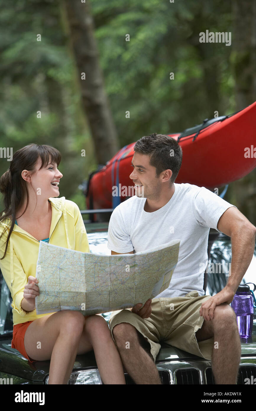 Couple with map sitting on car Stock Photo - Alamy