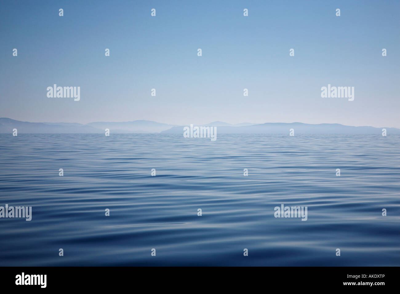 Ocean with hazy mountain shore Stock Photo - Alamy